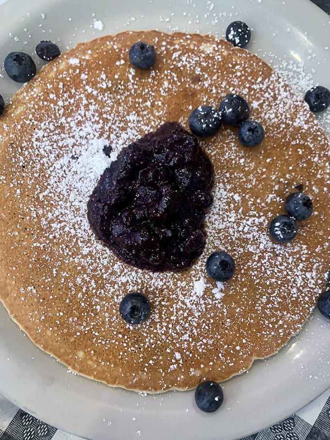 This pancake wears its blueberries like jewelry. The powdered sugar snowfall completes a breakfast that's more art than mere sustenance.