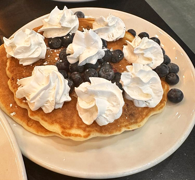 Blueberry pancakes topped with whipped cream clouds&mdash;proof that sometimes the simplest pleasures make the most profound breakfast statements.
