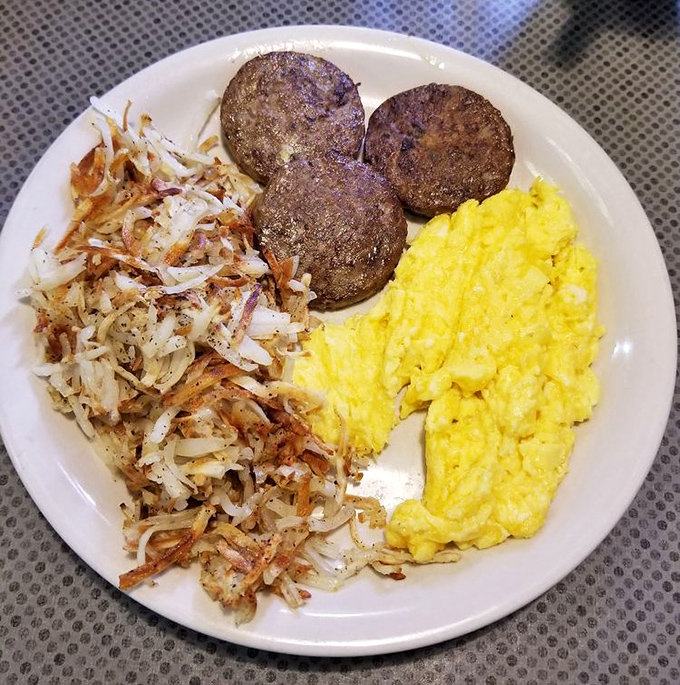 The breakfast trinity&mdash;fluffy scrambled eggs, perfectly browned sausage patties, and hash browns that look like they've earned their crispy edges through years of dedication.