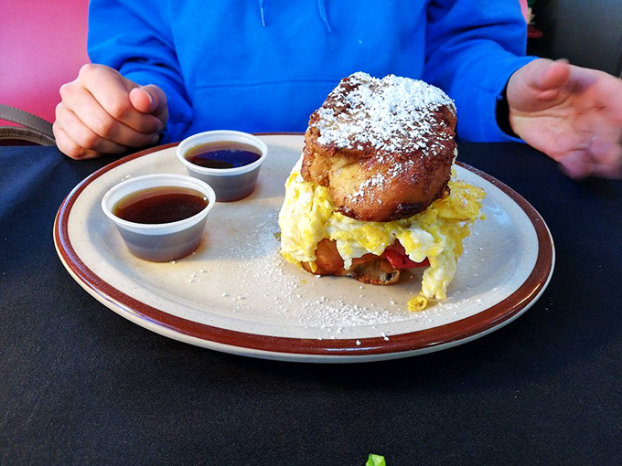 Breakfast reimagined: a powdered sugar-dusted challah bun embracing fluffy eggs. Two dipping sauces because important decisions shouldn't happen before coffee.