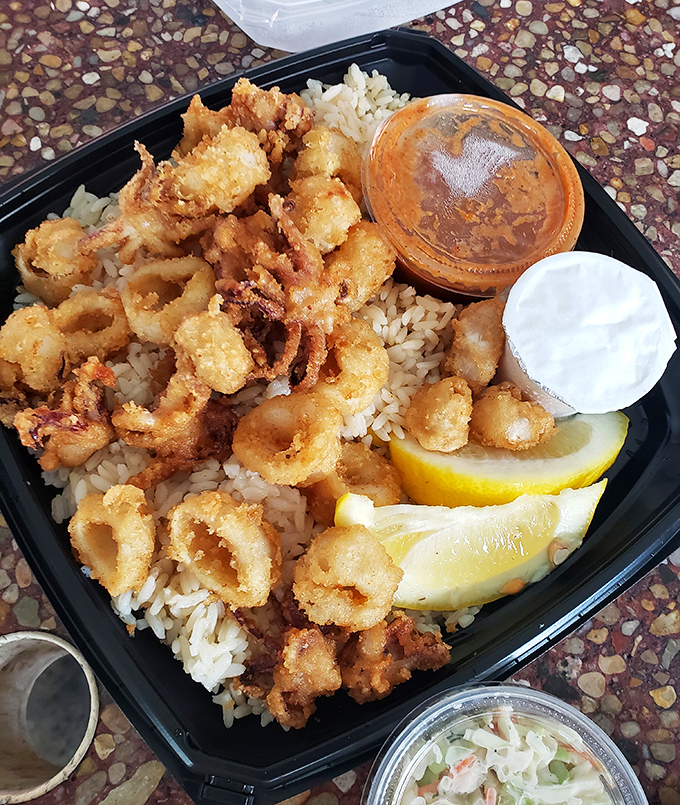 Crispy calamari that shatters with each bite, nestled on rice with lemon wedges standing by &ndash; no rubber bands here, just perfectly fried ocean rings.