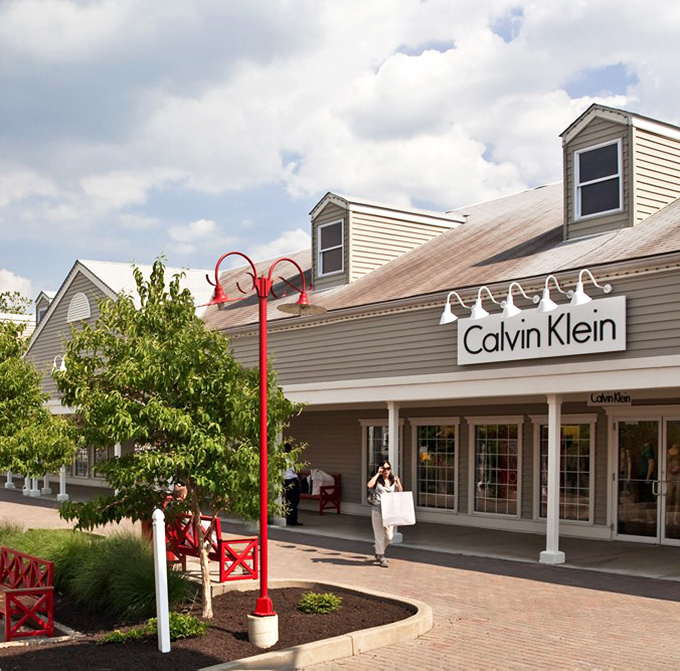 Calvin Klein's storefront welcomes shoppers with distinctive red lamp posts and benches for weary shopping companions.