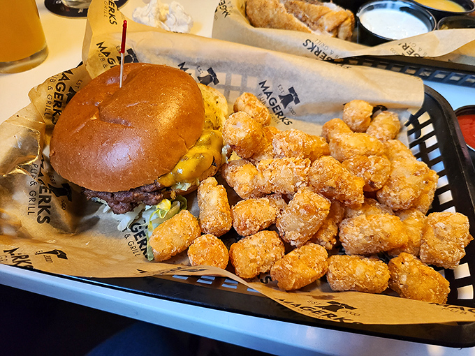 A perfectly grilled burger with golden tater tots—comfort food that speaks the universal language of "you're going to need a nap after this."
