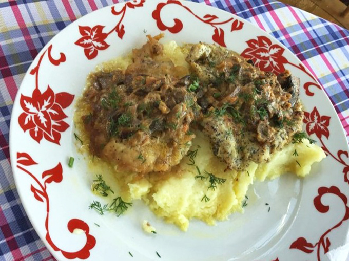 Chicken schnitzel resting on a cloud of mashed potatoes. The golden crust shatters with each bite, revealing juicy meat that's worth crossing state lines for.