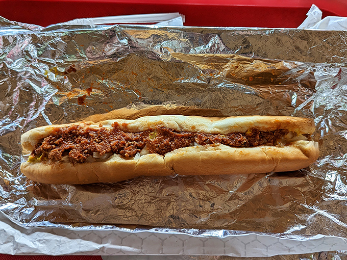 The chili dog in its natural environment: aluminum foil, paper boat, car dashboard. Some meals are worth the napkin investment and potential shirt casualties.