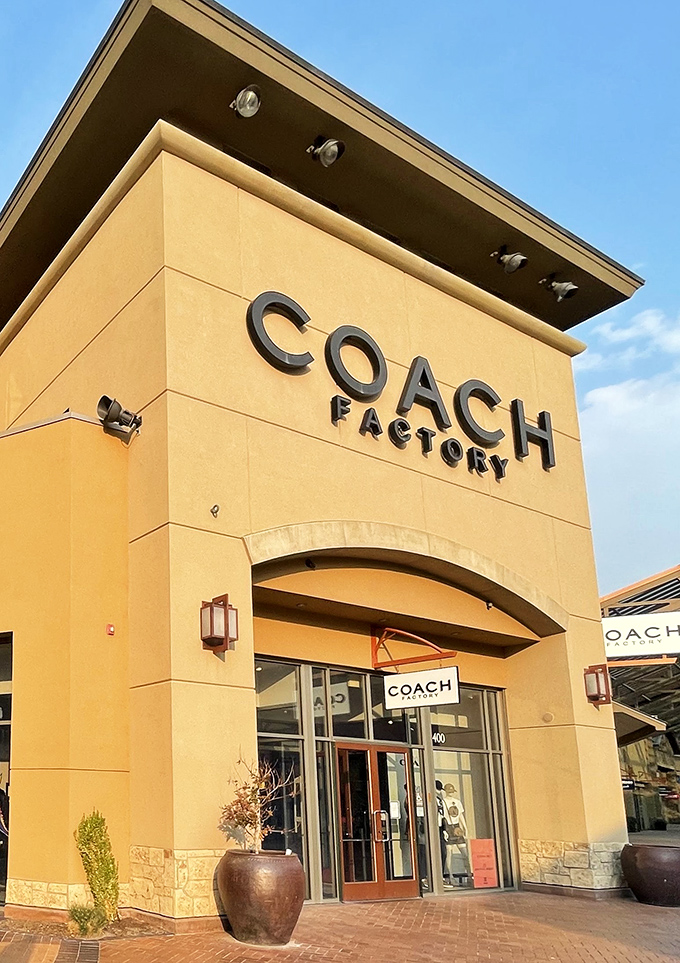 Coach Factory's entrance beckons with that signature yellow storefront, turning leather goods dreams into financially responsible reality.