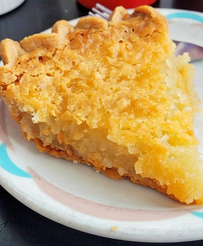 Coconut macaroon pie that would make your grandmother simultaneously proud and jealous. The flaky crust cradles a filling that's both familiar and mysteriously addictive.