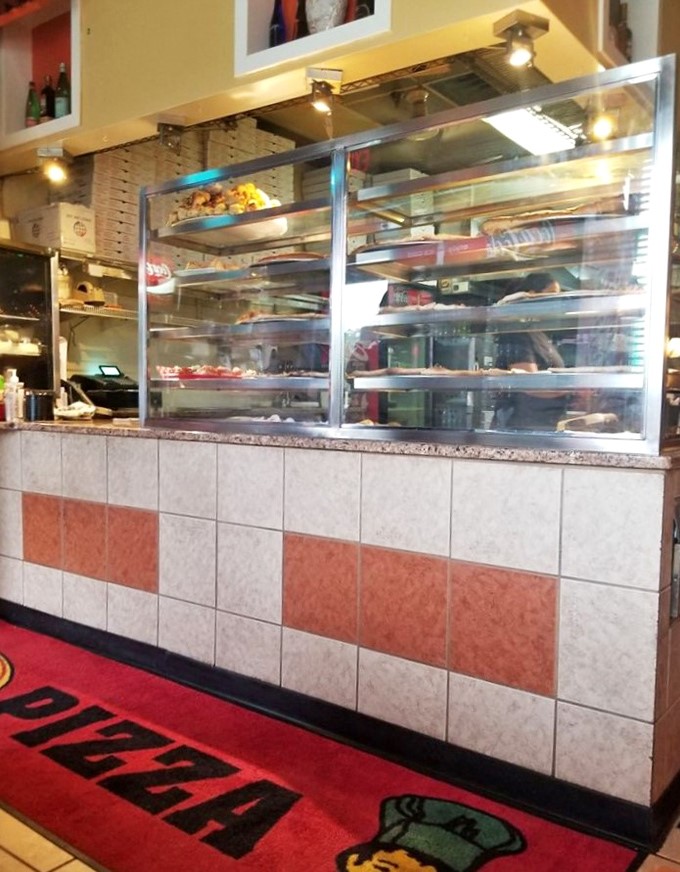 Behind this counter, culinary magic happens daily. The display case showcases Italian treasures that make choosing just one item nearly impossible.