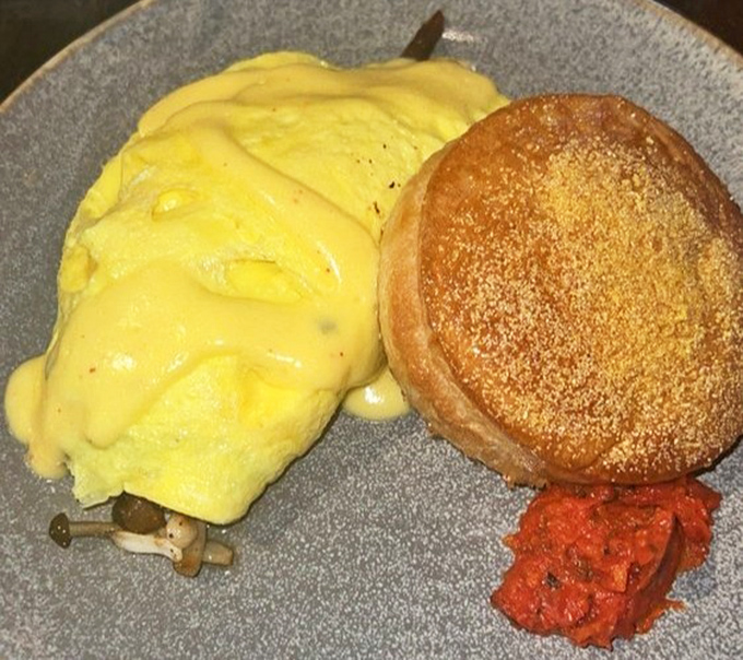 Sunshine-yellow eggs nestled against a golden English muffin with a splash of tomato jam &ndash; breakfast architecture at its finest.