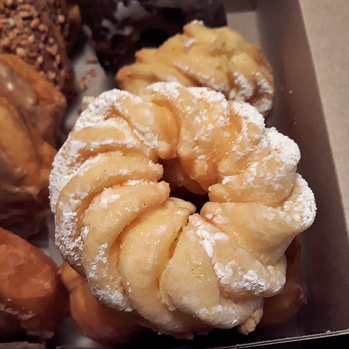 The flower-shaped cruller is architecture you can eat&mdash;delicate ridges dusted with powdered sugar, hiding a creamy custard center that's worth every calorie.