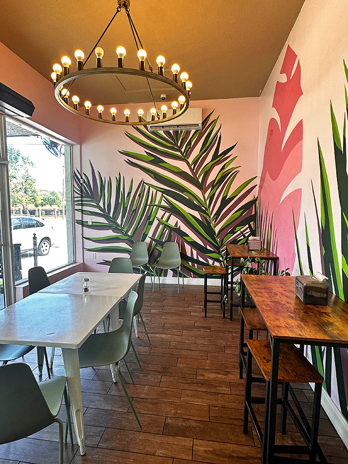 Tropical wall murals and mixed seating create a space where lingering over your sandwich feels not just allowed but encouraged.