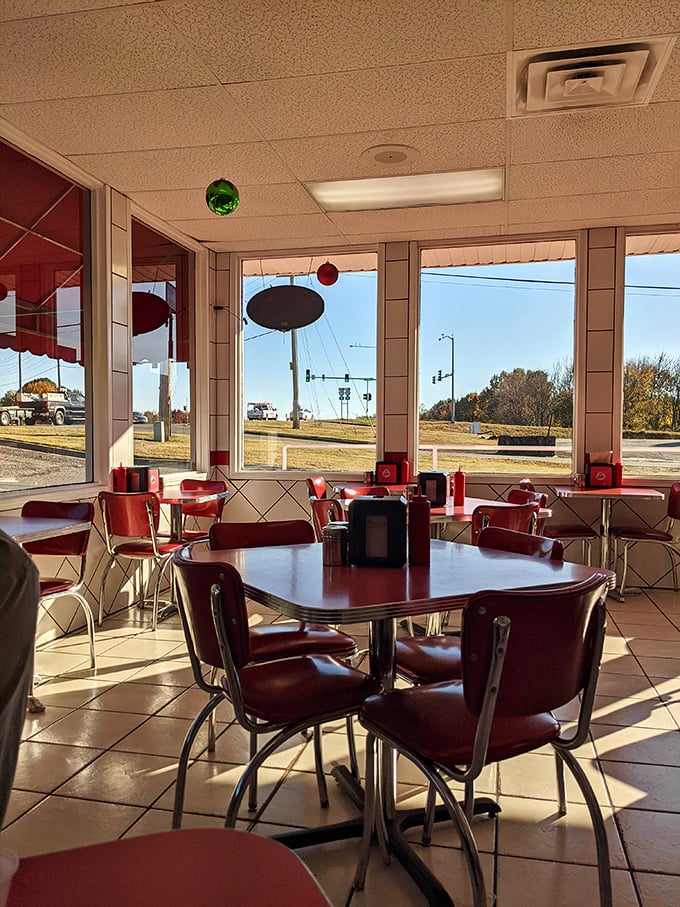 Sunlight streams through windows, illuminating those iconic red chairs like they're ready for their diner glamour shot.