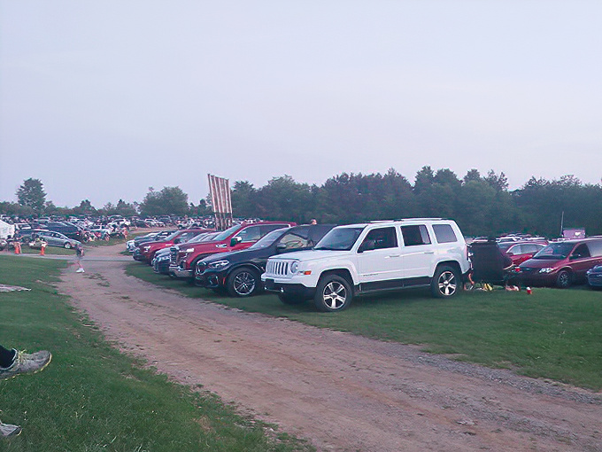 Cars line up like eager moviegoers themselves, each finding their perfect spot. The drive-in democracy: first come, best view.