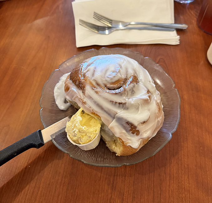 The cinnamon roll arrives like a decadent spiral galaxy of sweetness, with icing cascading down its curves like a sugary waterfall of joy.