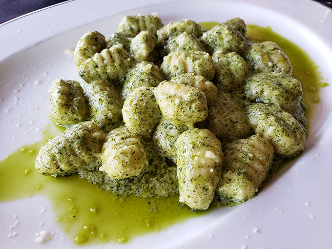 Gnocchi Pesto swimming in vibrant green basil oil &ndash; little pillows of potato pasta that look like they're lounging in a delicious herb spa.
