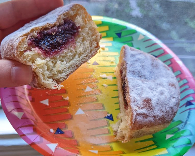 A jelly-filled delight that proves the best things in life come on colorful paper plates and leave powdered sugar on your shirt.