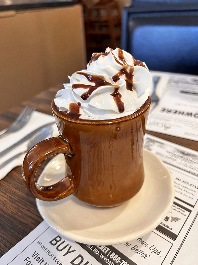 Hot chocolate that doesn't know the meaning of restraint. That whipped cream mountain with chocolate drizzle is pure joy in ceramic form.