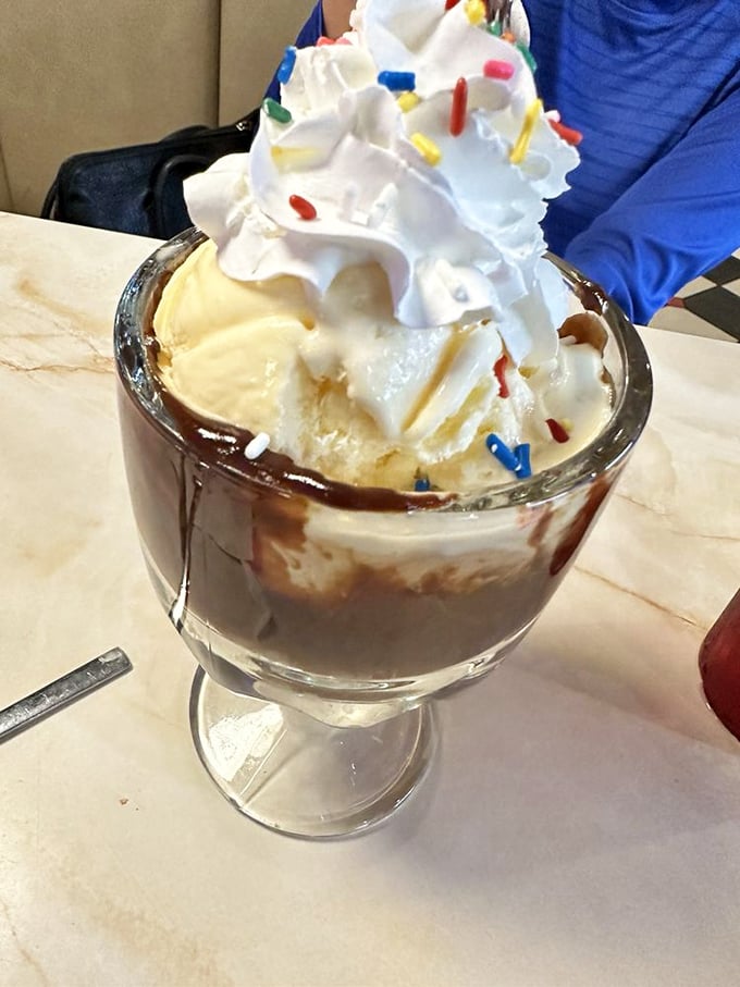 This hot fudge sundae topped with whipped cream and sprinkles is childhood joy served in a glass goblet.