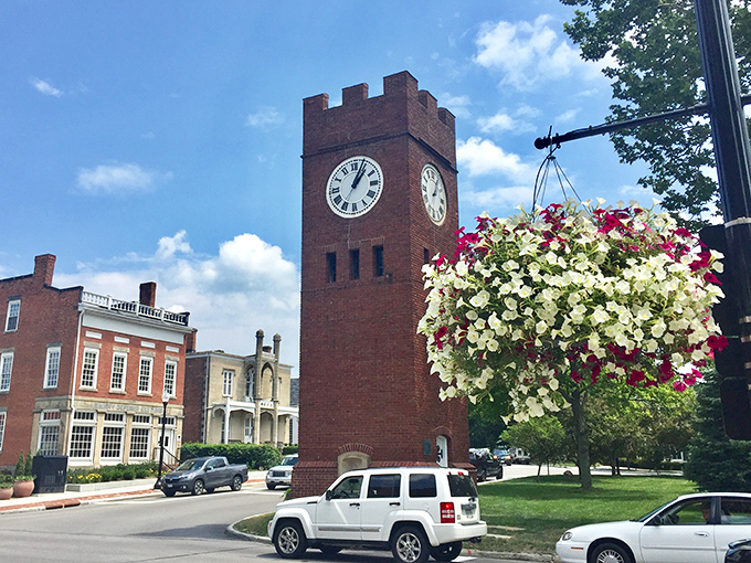 Hudson's Clock Tower stands tall amid hanging flower baskets, keeping time for generations while surrounded by seasonal beauty.