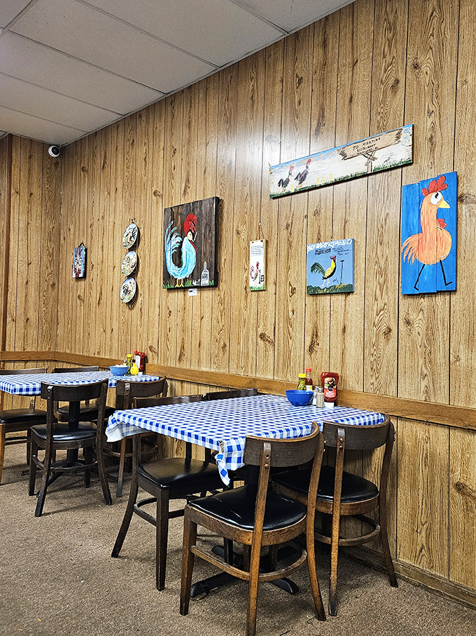 Chicken-themed art watches over diners like guardian angels of Southern cuisine. The blue checkered tablecloths are non-negotiable.