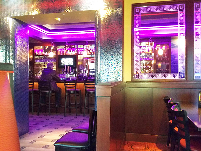 The bar area glows with purple neon and Greek key patterns, creating an atmosphere that's part Mediterranean, part nightclub, all inviting.