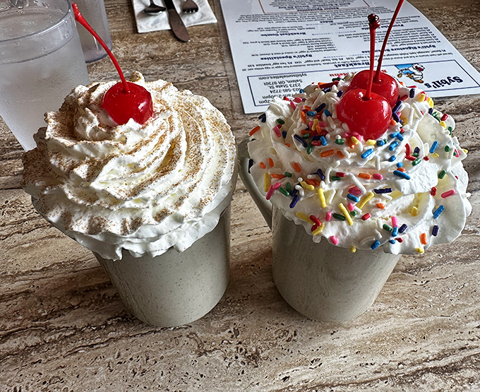 Milkshakes topped with whipped cream mountains and cherries&mdash;one classic, one festive with sprinkles&mdash;both guaranteed to bring smiles.