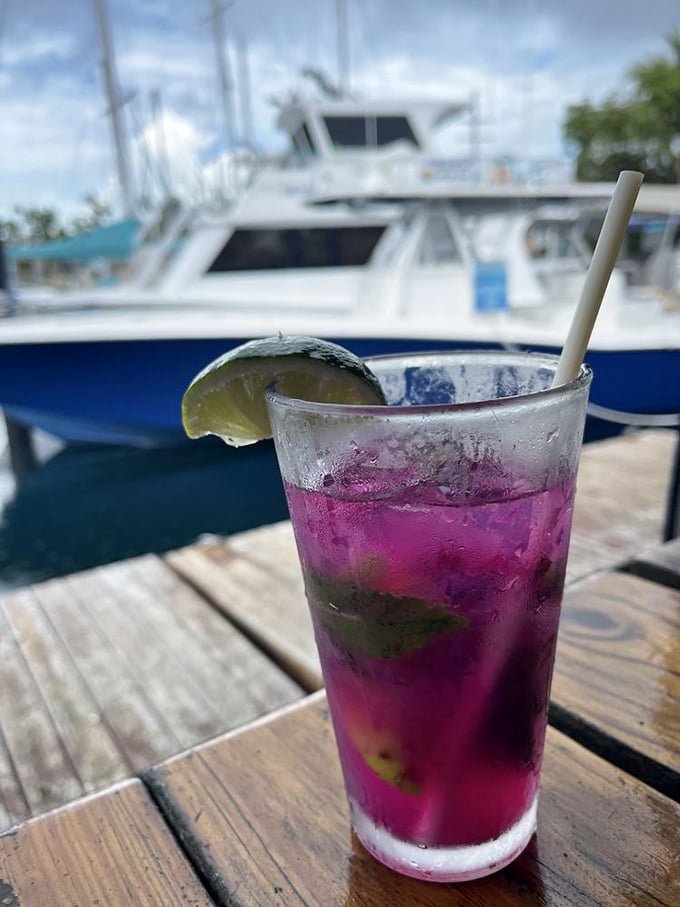 Nothing says "vacation mode activated" like a vibrant purple cocktail with boats in the background. The lime isn't garnish&mdash;it's essential equipment.