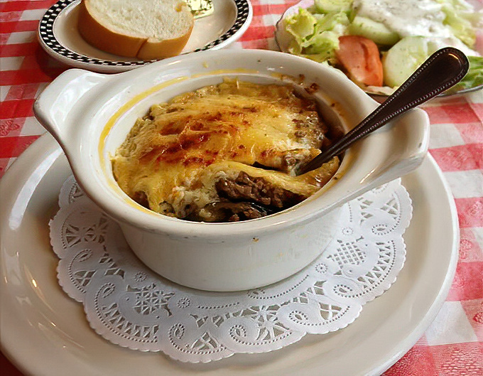 This bubbling, cheese-topped casserole isn't just food &ndash; it's a warm hug in a ceramic dish, served on a doily because comfort food deserves a proper presentation.