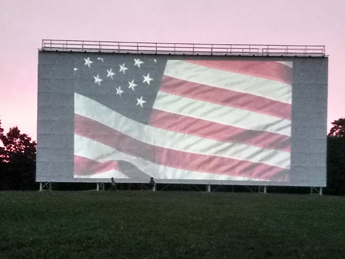 The American flag fills the massive screen before showtime, a patriotic prelude that reminds us some traditions are worth preserving.