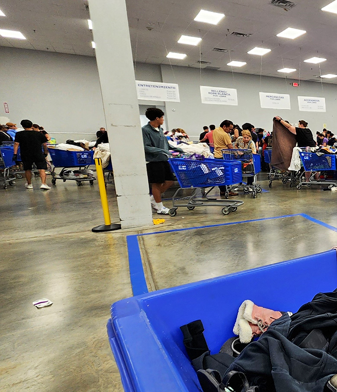 The blue bin battlefield where bargain hunters converge. Notice the shopping carts standing by, ready to be filled with unexpected treasures.