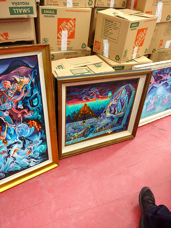 Psychedelic dreamscapes in gilded frames lean casually against moving boxes, proving one person's decluttering is another's living room masterpiece.