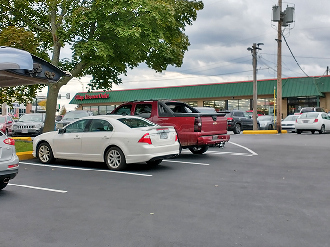 The unassuming exterior hides a universe of possibilities within. Cars gather like pilgrims at a shrine to secondhand splendor.