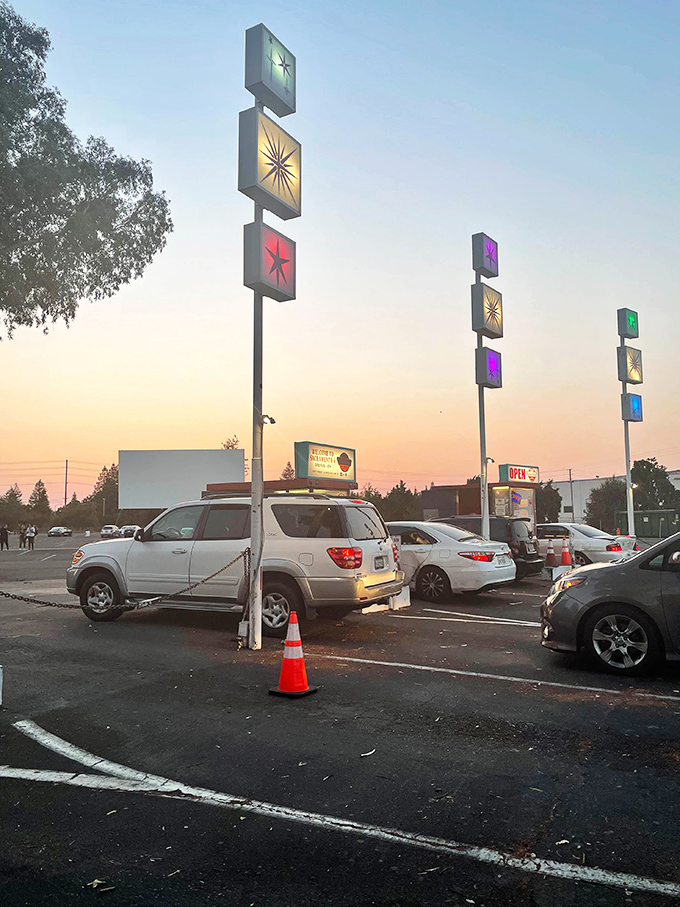 Retro-futuristic light towers stand like sentinels at dusk, their colorful panels guiding moviegoers to their spots as the sky fades to showtime.