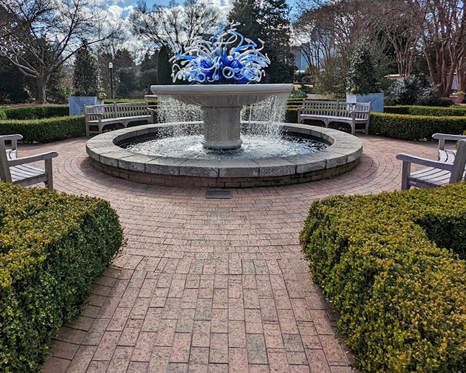 Blue tendrils dance above bubbling waters, this glass sculpture catching sunlight like frozen ocean waves in mid-splash.