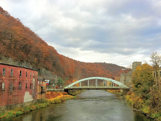 Fall foliage frames this elegant bridge like nature's own Instagram filter, creating a postcard-perfect scene that begs for a leisurely afternoon stroll.