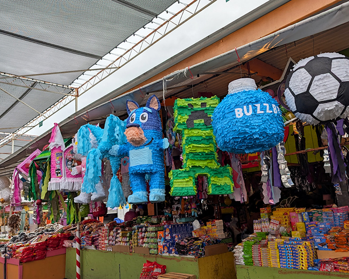 Pi&ntilde;atas that double as colorful suspended art. These festive creations hang like jubilant sentries, guarding aisles of candies and celebration supplies below.