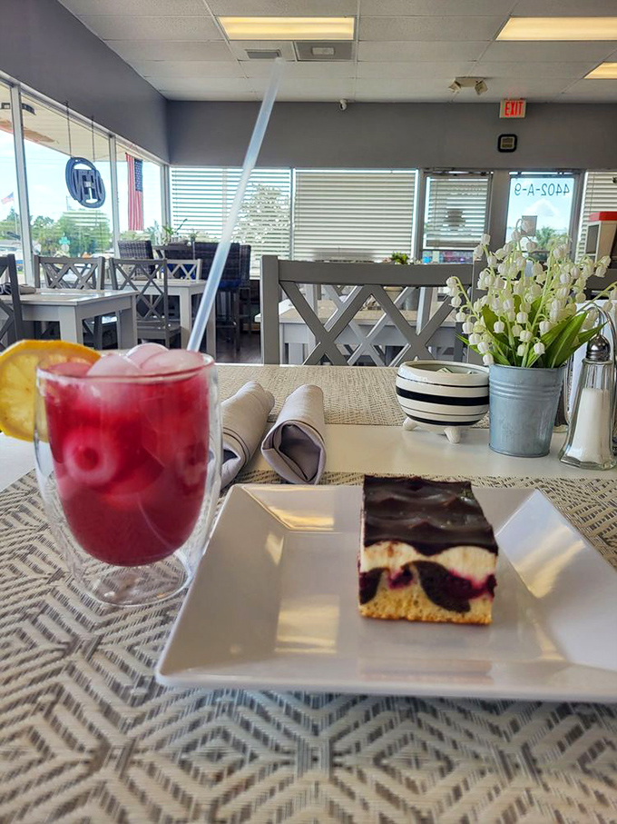 A slice of berry-studded cake alongside ruby-red lemonade&mdash;proof that sometimes the best vacation moments happen at a bakery table, not a beach.
