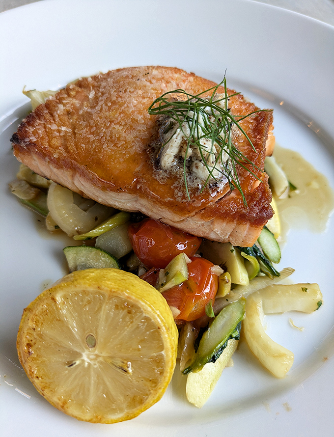 Salmon with skin so crispy it deserves its own fan club, resting on a garden of vegetables that didn't know they could taste this good.