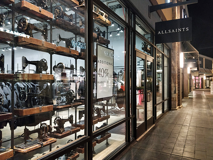 AllSaints' moody window display showcases vintage sewing machines alongside modern fashion. Industrial chic meets accessible price points.