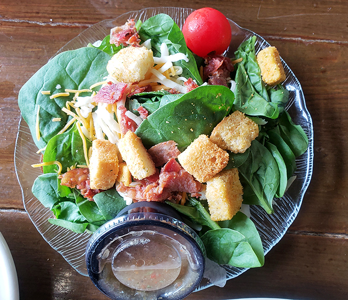 Even the salad gets the coastal treatment with fresh greens, cheese, and what appears to be bacon &ndash; because vegetables should never be boring.