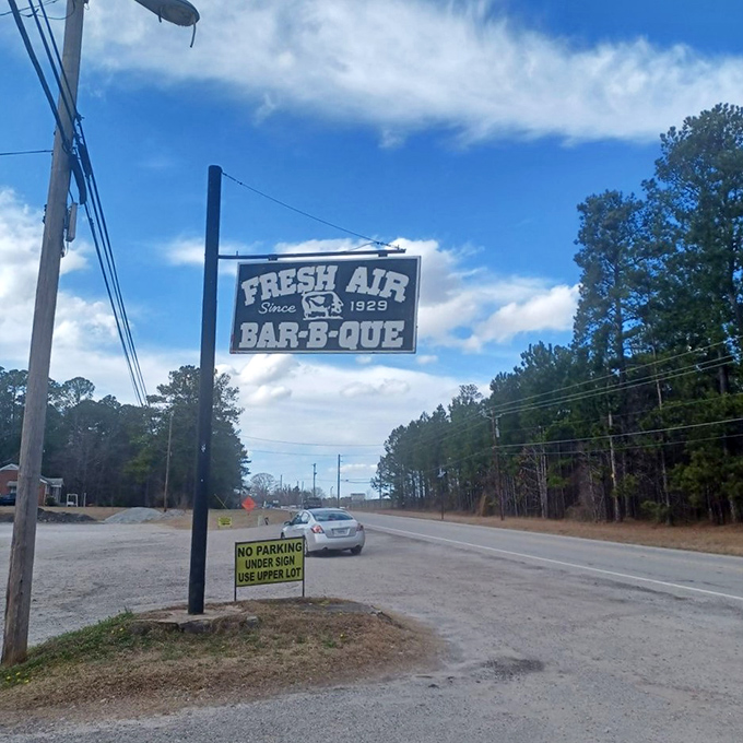 The roadside sign stands like a barbecue lighthouse, guiding hungry travelers to a destination worth every mile of the journey.