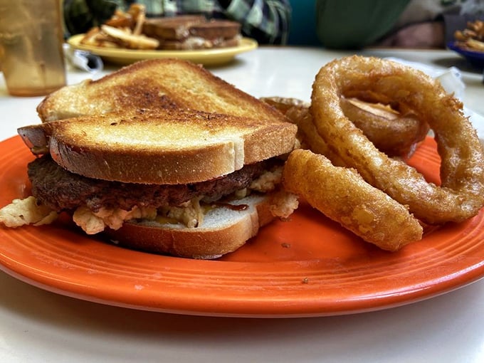 This sandwich and onion ring duo isn't just lunch&mdash;it's edible therapy after a long morning, served on a bright orange plate that matches your mood after the first bite.
