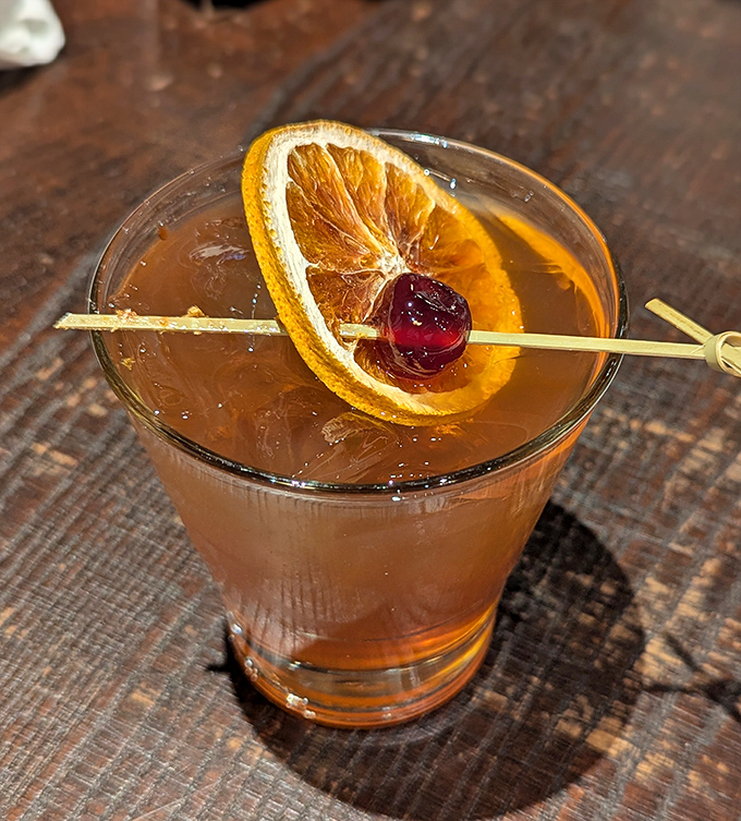 The Smoked Old Fashioned &ndash; where bourbon meets barbecue philosophy in liquid form, garnished with a perfect orange slice and cherry.