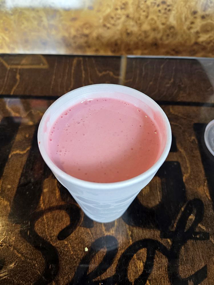 The strawberry shake—thick, pink, and perfect—offers sweet relief between bites of savory burger goodness.