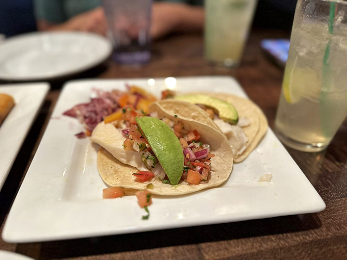 Fish tacos that look like they're dressed for a party, complete with avocado slices and colorful garnishes galore.