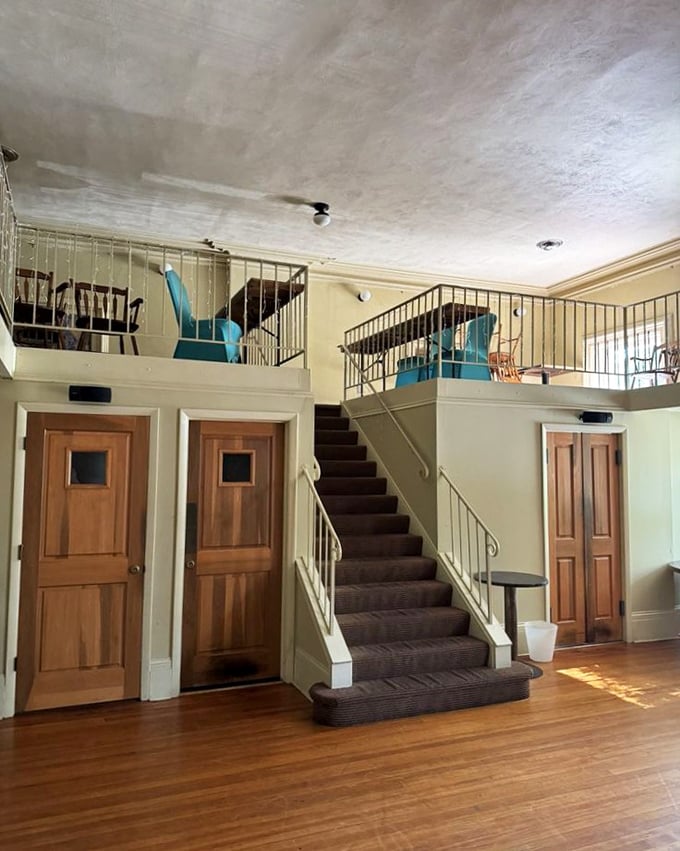 The mezzanine seating area reveals the building's schoolhouse bones. Those wooden doors probably have stories that would fill another menu.