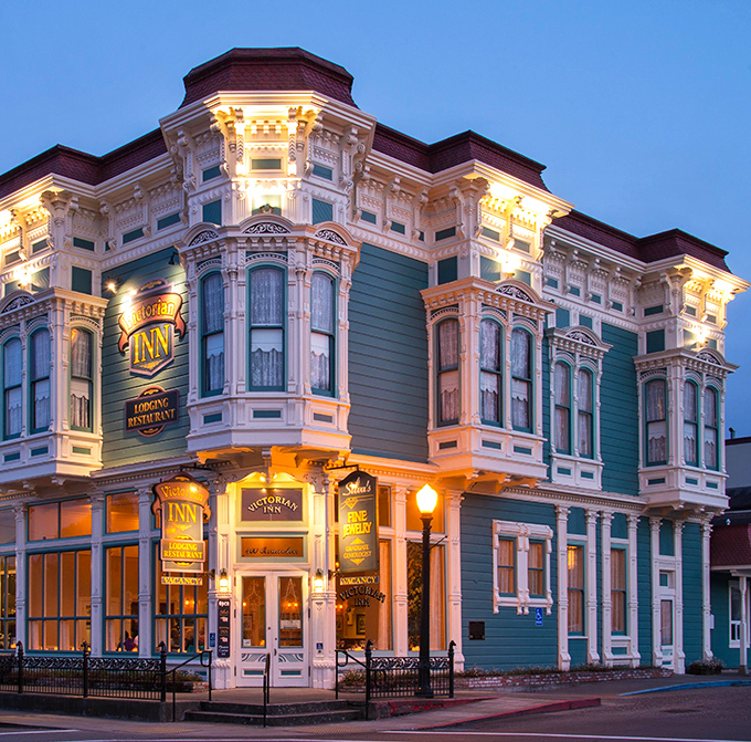 The Victorian Inn glows at twilight like a jewel box, its ornate details illuminated to showcase craftsmanship you simply don't see in modern buildings.