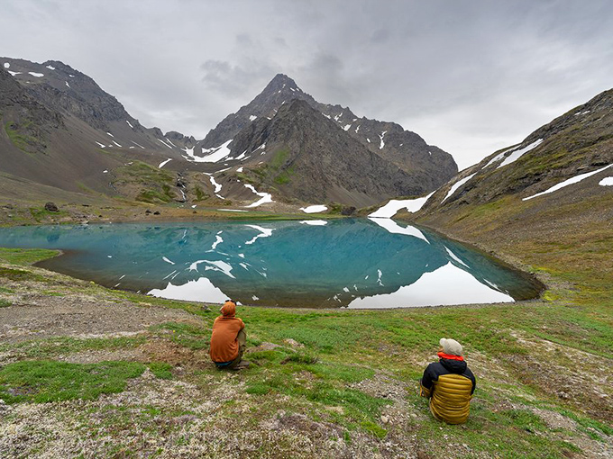 Two adventurers pause to absorb the turquoise alpine lake's majesty. When Mother Nature decides to flex her color palette skills, the only appropriate response is silent awe.