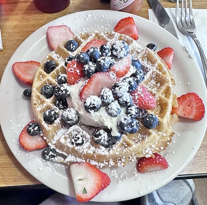 Berry-crowned waffle perfection that makes you question why people eat anything else for breakfast. The powdered sugar snowfall is just showing off.