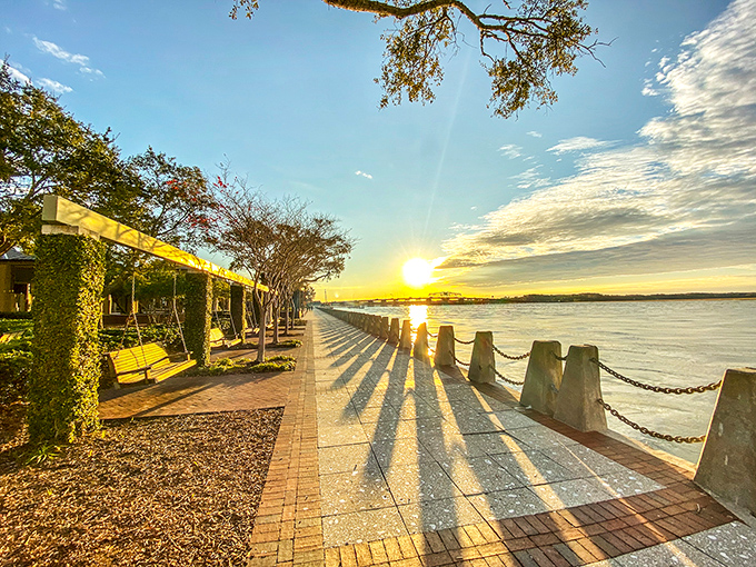 Sunset casts golden shadows along Beaufort's waterfront promenade. This daily light show transforms ordinary concrete into a runway of long shadows and warm memories.